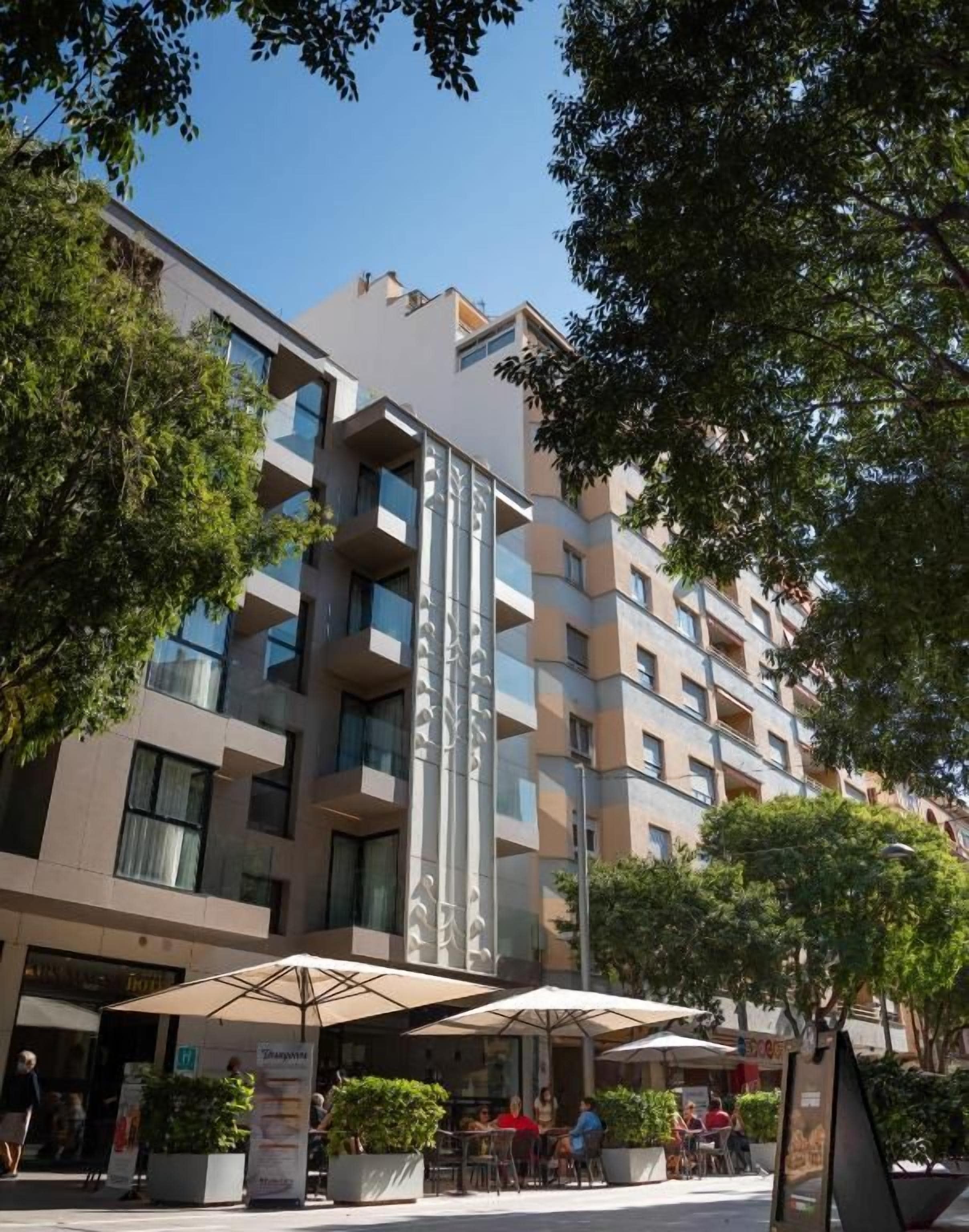 Um hotel com vários andares, área de estar ao ar livre e vegetação.