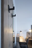 Um interior moderno com parede de madeira, mesa de jantar com cadeiras e duas luminárias fixadas na parede.