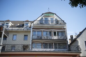 Um hotel com uma placa grande que diz "HOTEL", várias varandas com grades de ferro ornamentadas e um estilo arquitetônico clássico.