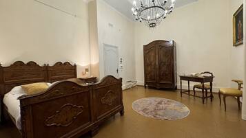 Quarto com cama de madeira, luminária pendente, guarda-roupa, escrivaninha com cadeira e tapete.