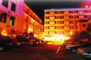 Hotel com vários andares e estacionamento em frente.