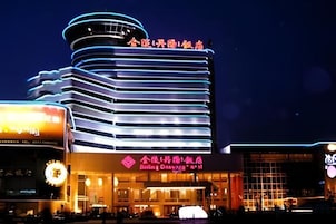 Um hotel de vários andares com design moderno, apresentando uma estrutura circular proeminente no topo e sinalização iluminada.