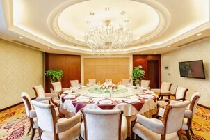 Uma sala de conferências com uma mesa redonda, cadeiras e um candelabro.