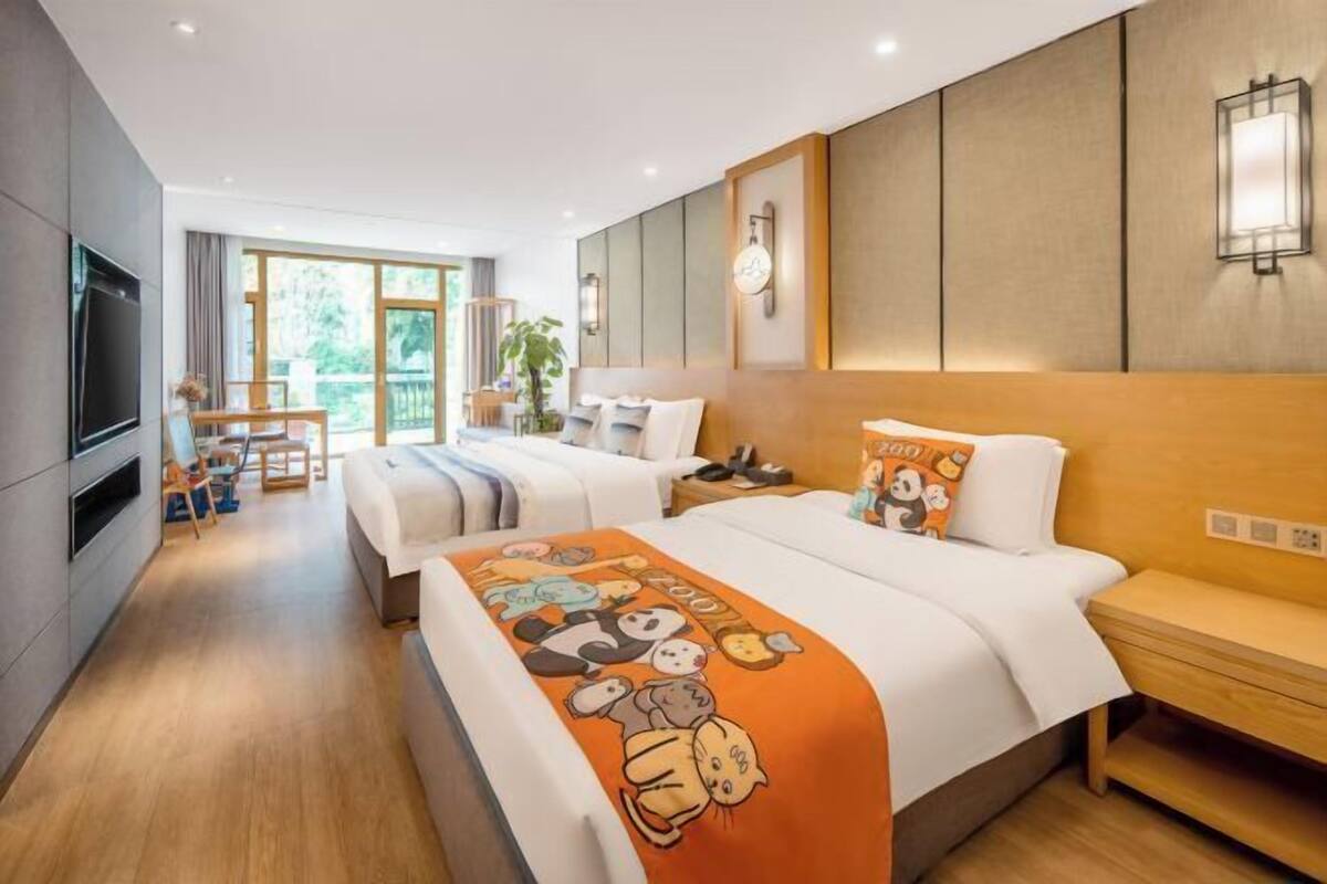 Quarto de hotel com uma cama grande, uma escrivaninha e uma televisão.
