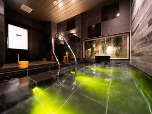 Um spa moderno com piso aquecido, um balde de madeira e uma grande janela com plantas.