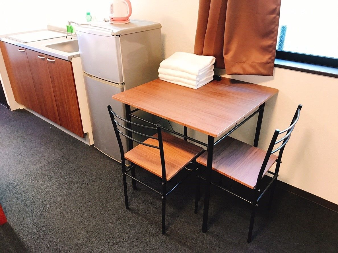 Uma cozinha compacta com pia, um refrigerador pequeno e uma mesa com cadeiras.