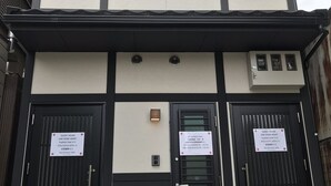 Um edifício de dois andares com paredes externas em preto e branco, duas portas pretas com painéis de vidro e uma pequena placa acima da porta.