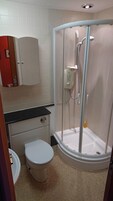 Um banheiro com vaso sanitário, box de chuveiro e pia.