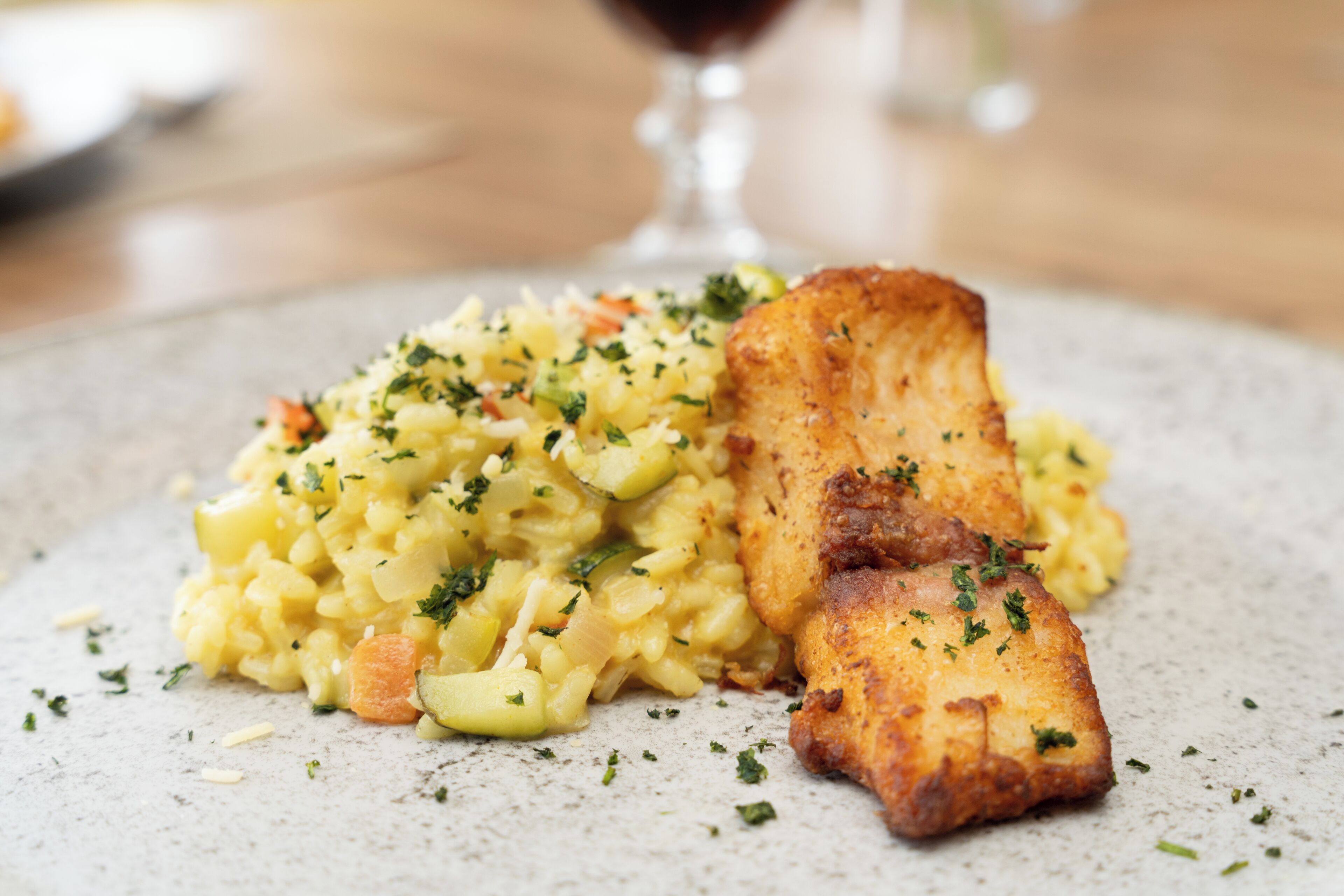 Um prato com um pedaço de peixe grelhado e um acompanhamento de risoto.