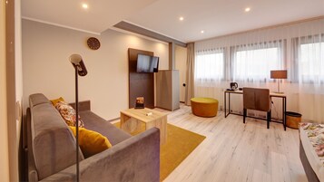 Uma sala de estar moderna com sofá, mesa de centro, televisão e área de jantar com mesa e cadeiras.