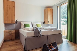 Quarto com cama, armários de madeira, mesa de cabeceira e vista pela janela.
