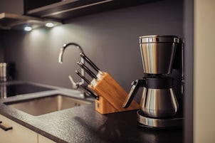 Cozinha moderna com cafeteira, porta-facas e pia.