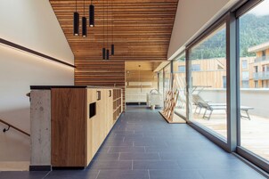 Interior moderno com teto de madeira, balcão de recepção e vista para o exterior.