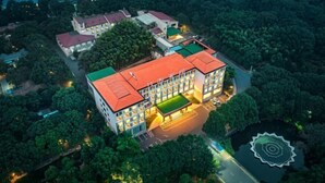 Vista aérea de um hotel com vários edifícios, cercado por vegetação densa.
