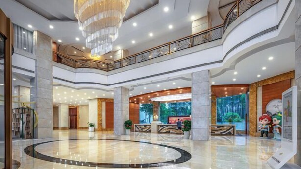 Um hall amplo com um lustre imponente, um balcão de recepção e um design de piso circular.