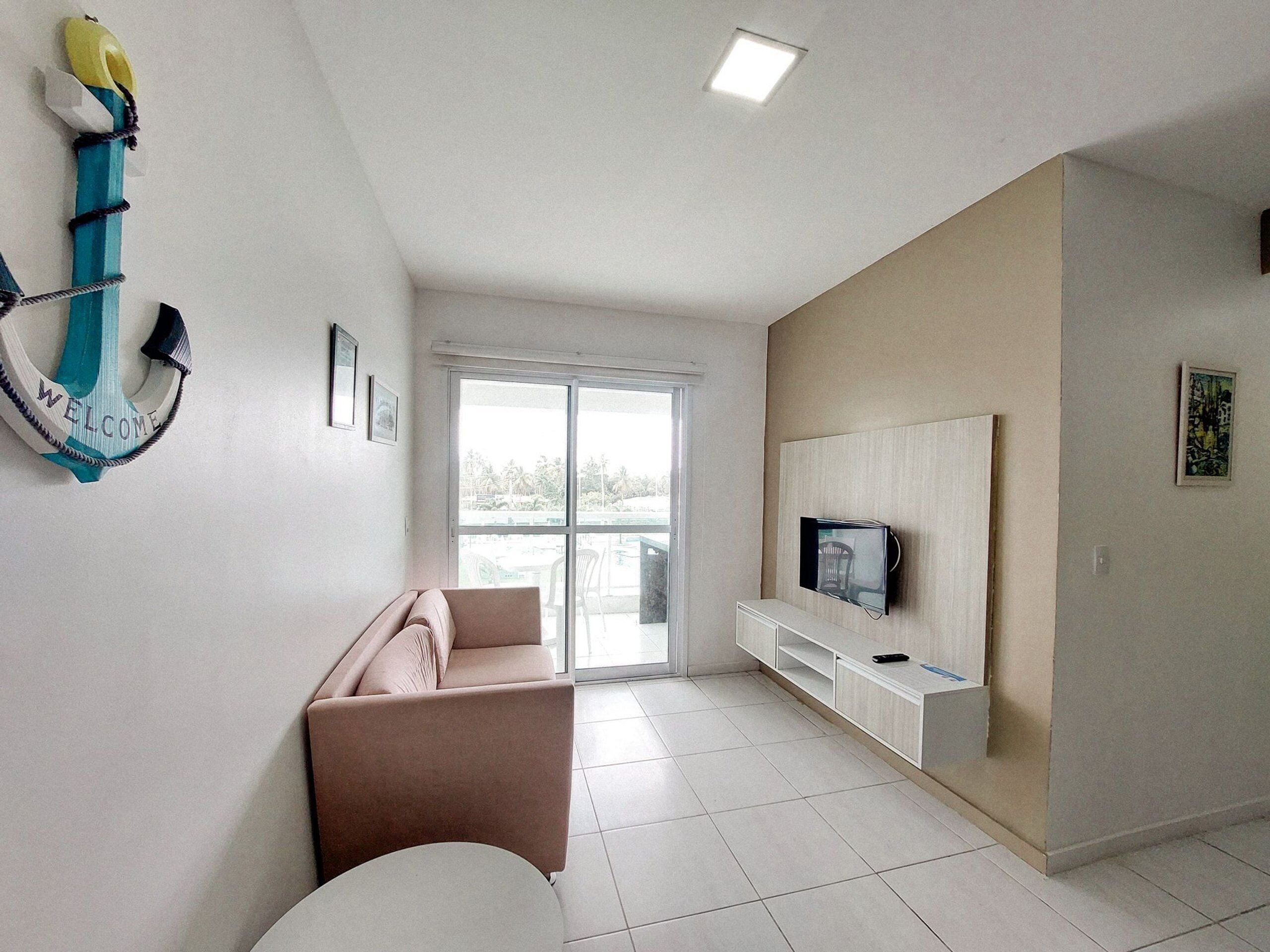 Uma sala de estar moderna com sofá, televisão e uma janela ampla.