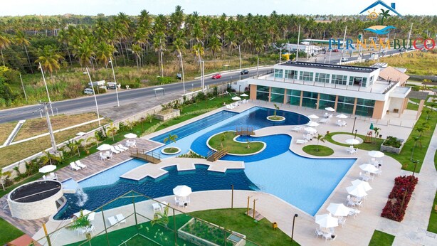 Um hotel moderno com uma piscina grande, área de estar ao ar livre e um gramado bem cuidado.