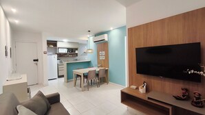 Uma sala de estar moderna com televisão de tela plana, um sofá e um espaço de jantar com mesa e cadeiras.