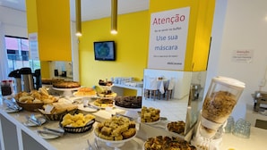 Buffet com diversos alimentos e aviso para uso de máscara.