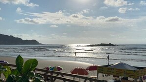 Uma praia com guarda-sóis, uma tenda e uma placa.