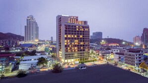 Um hotel moderno com vários andares, uma placa chamativa e fachada bem iluminada.