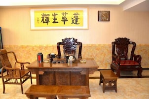 Quarto tradicional com escrivaninha de madeira, cadeiras e uma grande obra de arte emoldurada na parede.