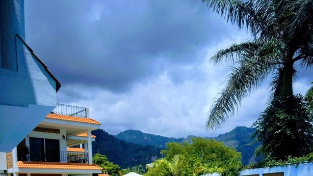 Piscina com vista desobstruída da paisagem circundante, incluindo uma casa e montanhas ao fundo.