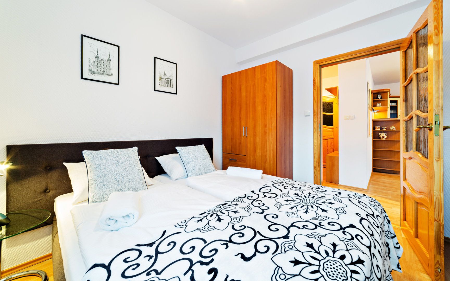 Quarto com uma cama grande, um guarda-roupa de madeira e duas fotografias emolduradas na parede.