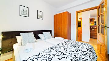 Quarto com uma cama grande, um guarda-roupa de madeira e duas fotografias emolduradas na parede.
