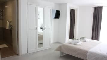 Quarto moderno com cama, guarda-roupa, televisão e zona de chuveiro.