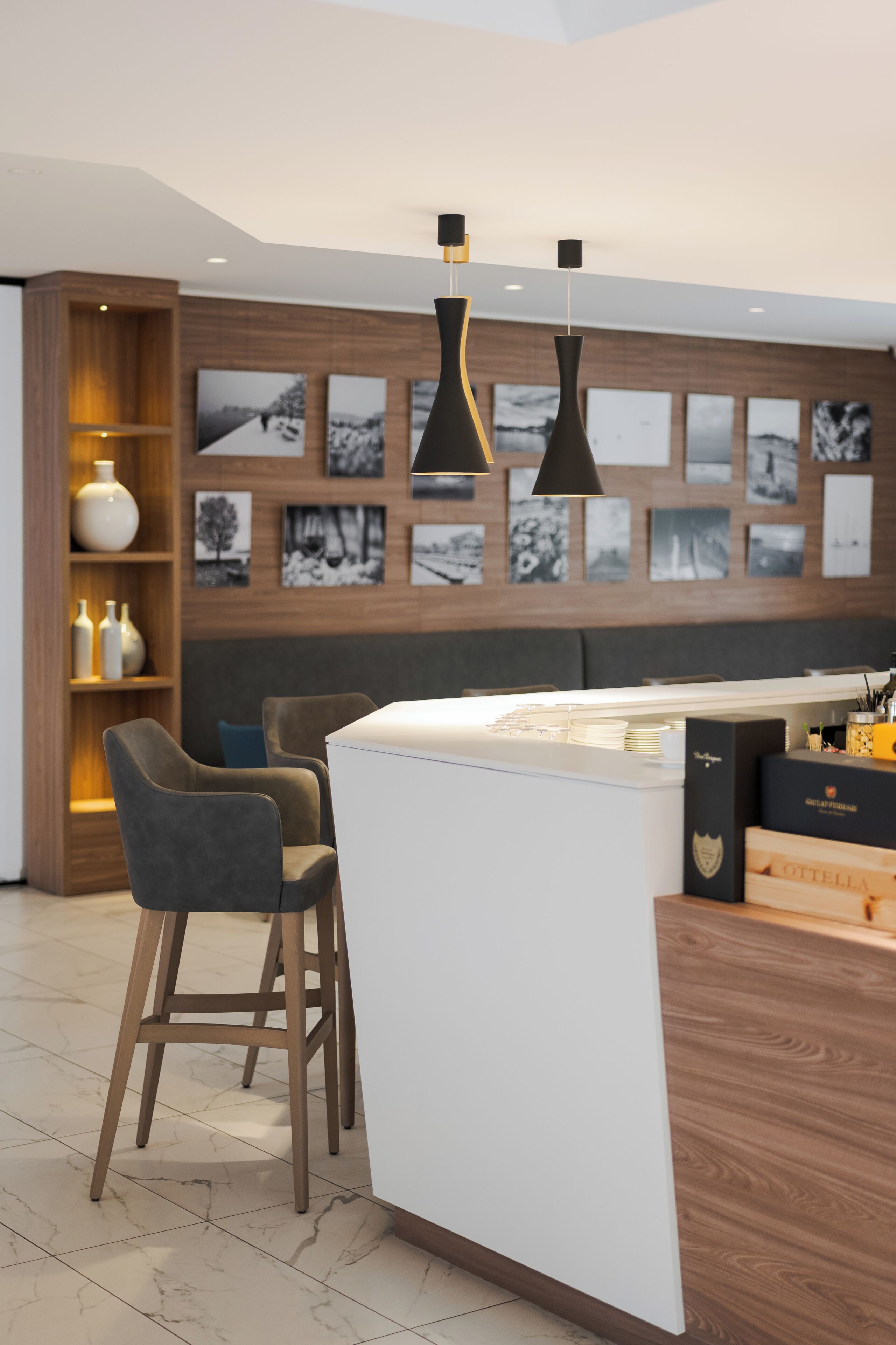 Uma cozinha moderna com uma ilha central, banquetas de bar, iluminação pendente e uma parede decorada com fotografias a preto e branco.