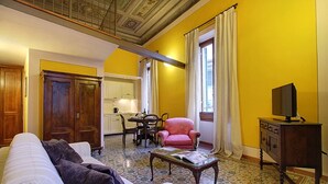 Sala de estar com sofá, poltrona e televisão sobre um móvel de madeira.