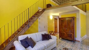 Um quarto com um sofá branco, uma escada de madeira e um guarda-roupa grande de madeira.