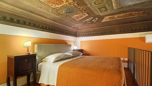 Quarto com uma cama grande, mesa de cabeceira com abajur e decoração no teto.