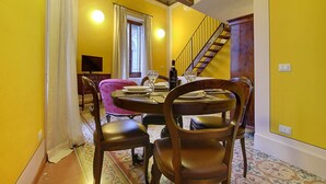 Uma sala de jantar com uma mesa redonda, quatro cadeiras e uma escada que leva a um andar superior.