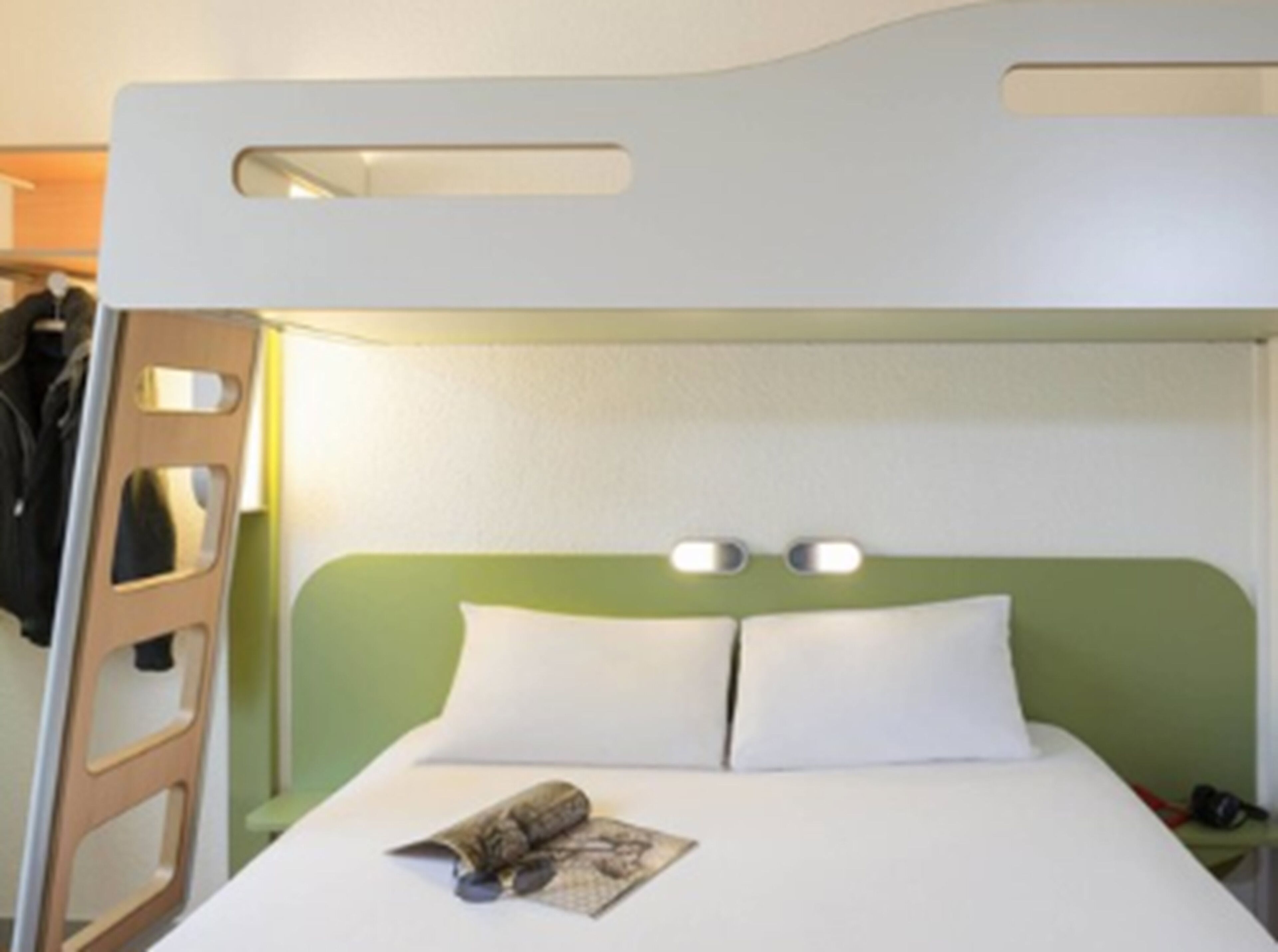 Uma cama de solteiro com cabeceira verde, uma mesinha de cabeceira e um abajur.
