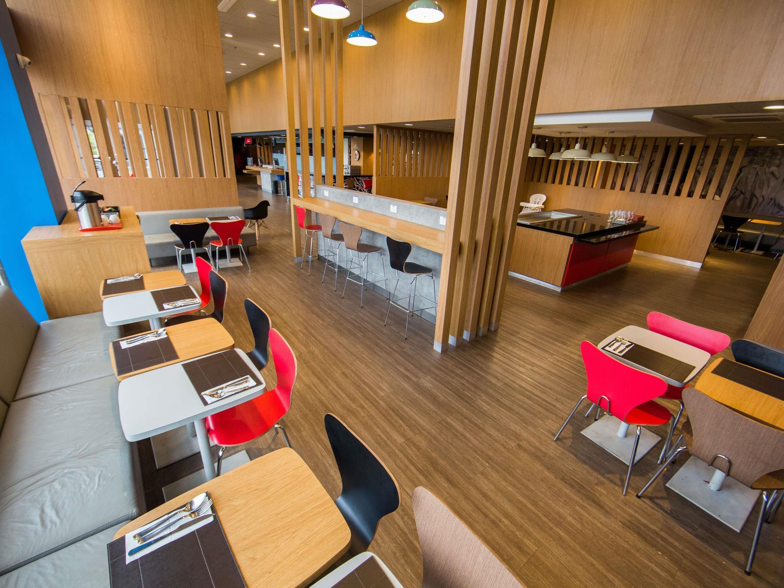 Restaurante moderno com painéis de madeira, área de bar e diferentes disposições de assentos.