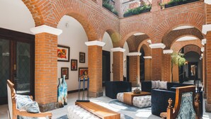 Um hall amplo com arcos de tijolo, um banco de madeira, sofás e uma grande janela.