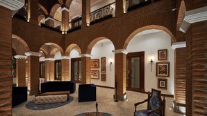 Um hall espaçoso com arcos de tijolo, um piano de cauda, assentos confortáveis e obras de arte nas paredes.