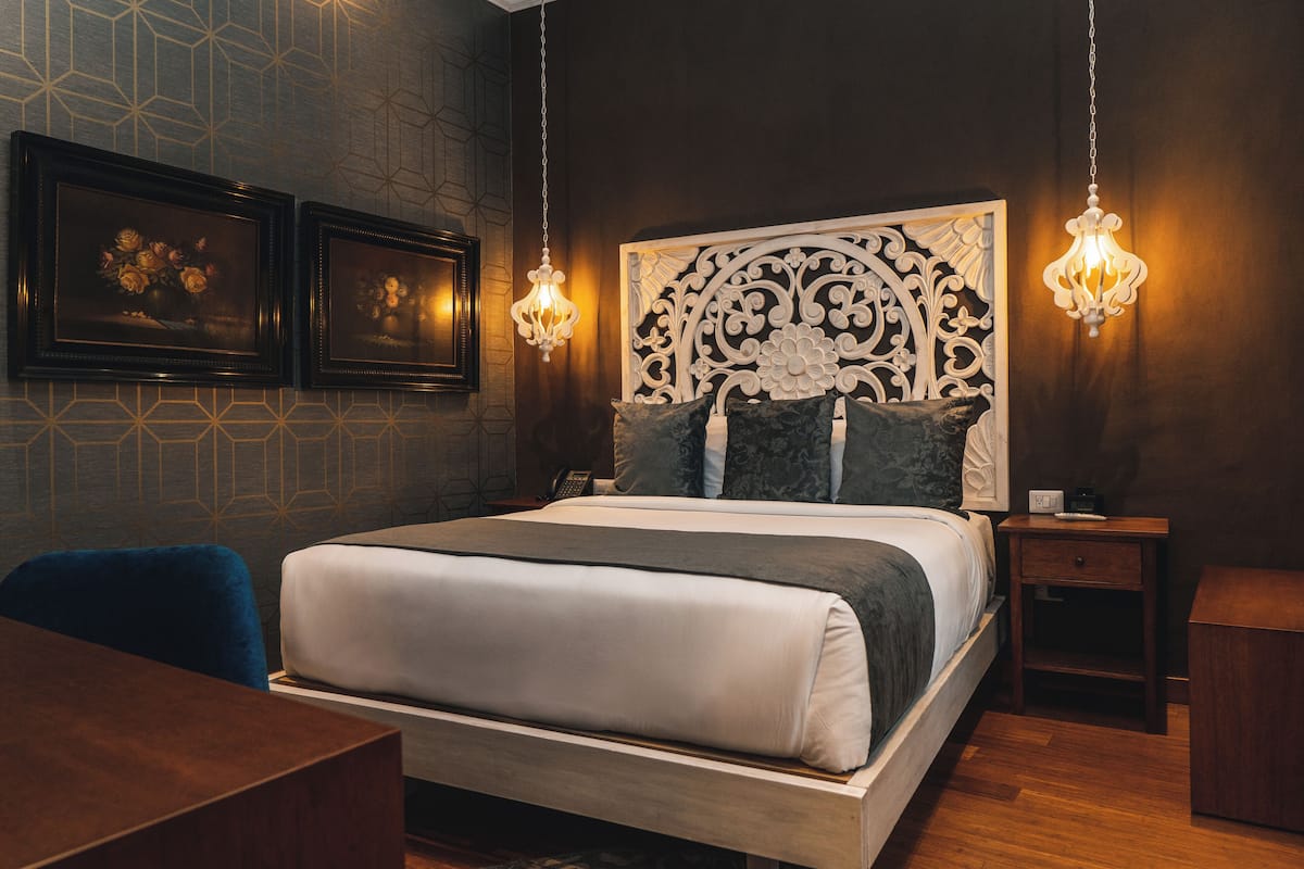 Quarto moderno com uma cama grande, duas mesas de cabeceira e uma cabeceira decorativa.