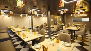 Um restaurante com mesas preparadas para refeições, decorações florais penduradas e um letreiro de neon na parede.