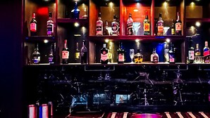 Um bar com prateleiras cheias de garrafas de bebidas e copos.