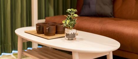 Uma mesa branca com uma planta e três canecas marrons sobre uma bandeja.