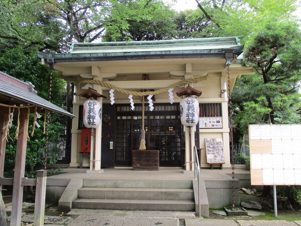 Um edifício tradicional japonês com telhado telhado, pilares de madeira e escadaria de pedra que leva à entrada.