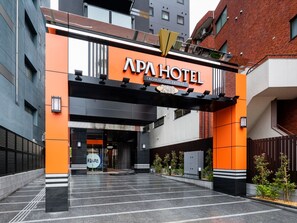 A entrada do APA HOTEL com design moderno, destacando um esquema de cores vibrante em laranja e preto, e o número '298' exibido em destaque sobre a entrada.