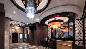 Um saguão de hotel moderno com um lustre imponente, um balcão de recepção e um posto de check-in.