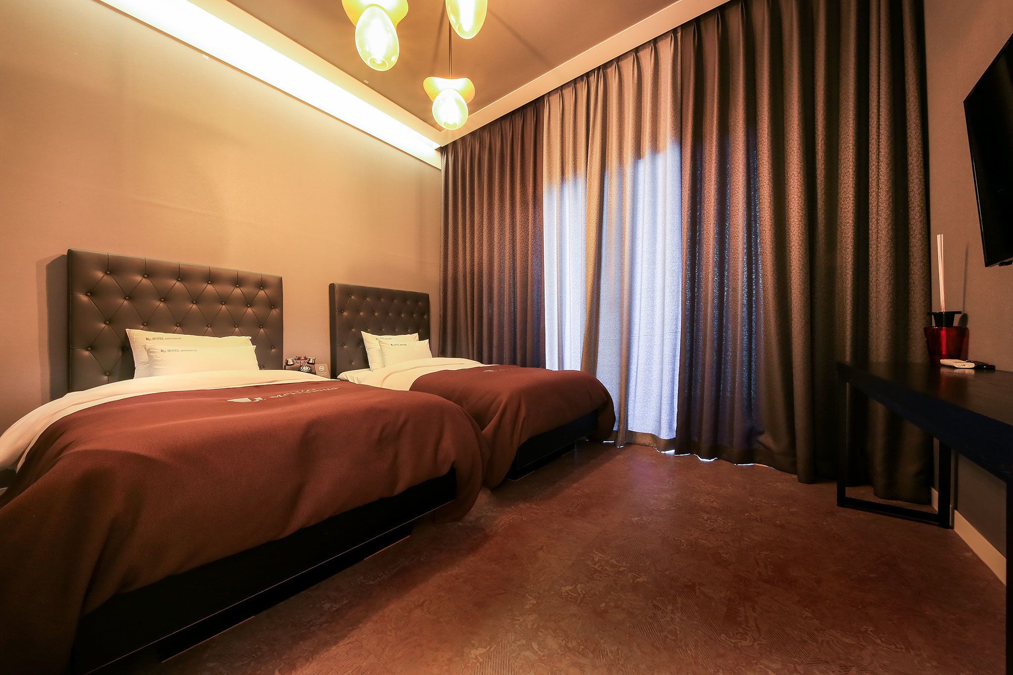 Quarto de hotel com duas camas, uma escrivaninha e uma televisão.