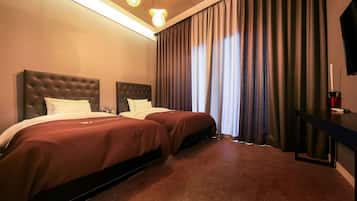 Quarto de hotel com duas camas, uma escrivaninha e uma televisão.