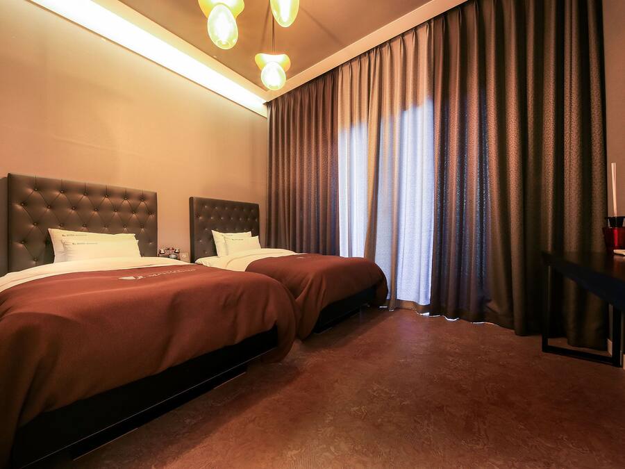 Quarto de hotel com duas camas, uma escrivaninha e uma televisão.