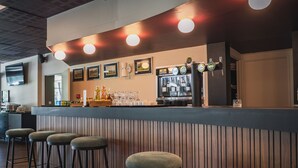 Uma área de bar com banquetas, balcão e refrigerador com garrafas.